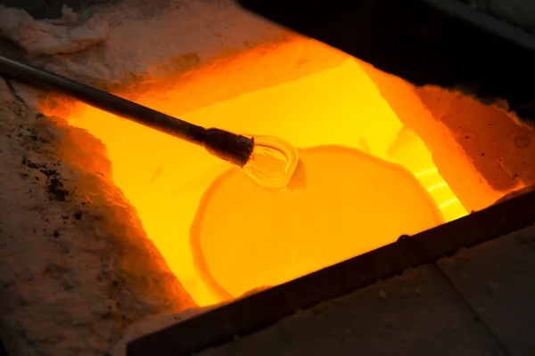 Handmade figure of melted glass, a glass blower working molten glass on ...