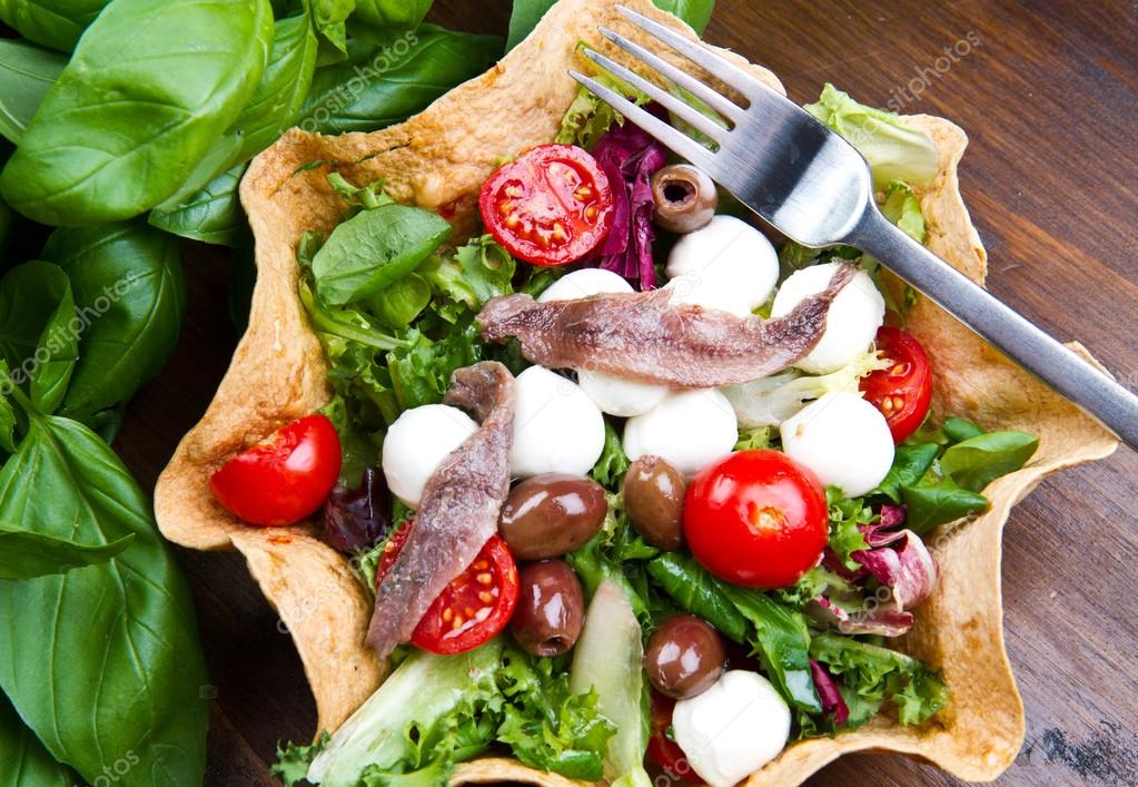 Mixed salad with mozzarella and anchovy in a bread basket Stock Photo ...