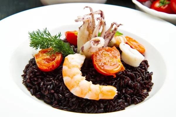 Black rice with sliced squids ,prawns and tomato on white plate Stock ...