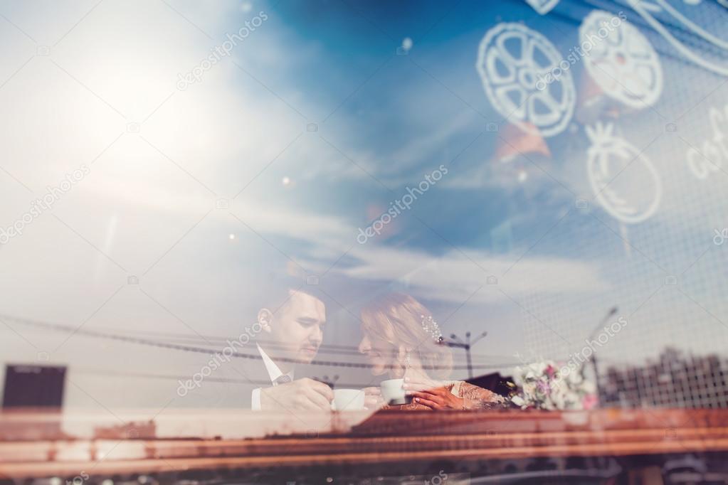 Bride and groom drinking coffee at an outdoor cafe. Reflections Stock ...