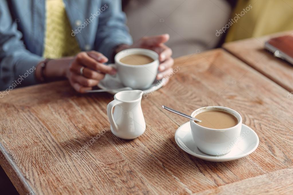 Two cups of coffee with woman hands on the wooden table in cafe Stock ...