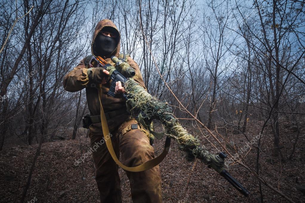 Sniper wearing camouflage suit with rifle walk in the woods Stock Photo ...