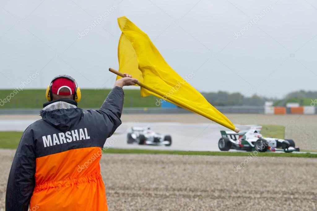 Marshal waving yellow flag — Stock Photo © Corepics #56326691
