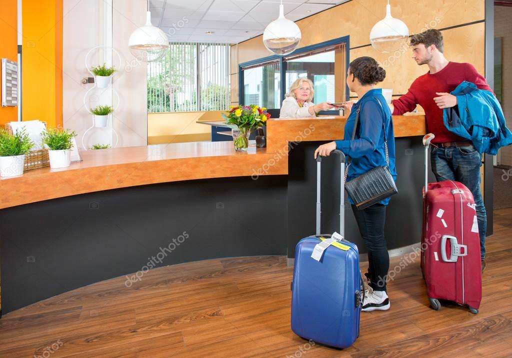 Young travelers at hotel check in — Stock Photo © Corepics #76770697
