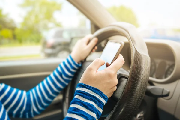 Woman driving car and texting message on smartphone - Stock Image ...