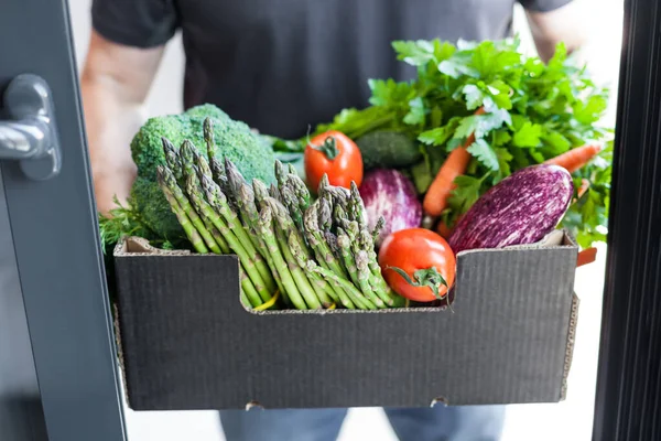 Fresh organic greens and vegetables delivery. Man hands holding box ...