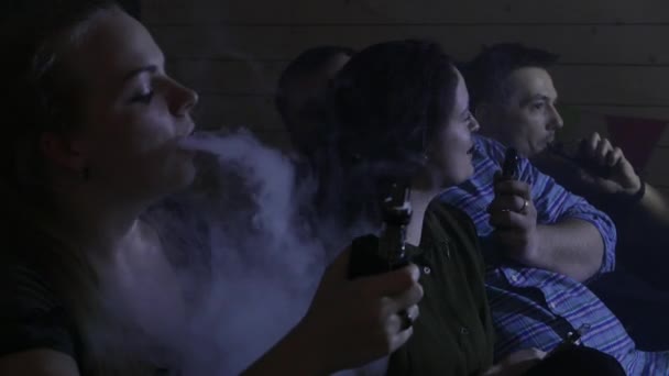 A group of people vaping, inhaling and exhaling large clouds of smoke ...