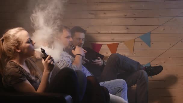 A group of people vaping, inhaling and exhaling large clouds of smoke ...
