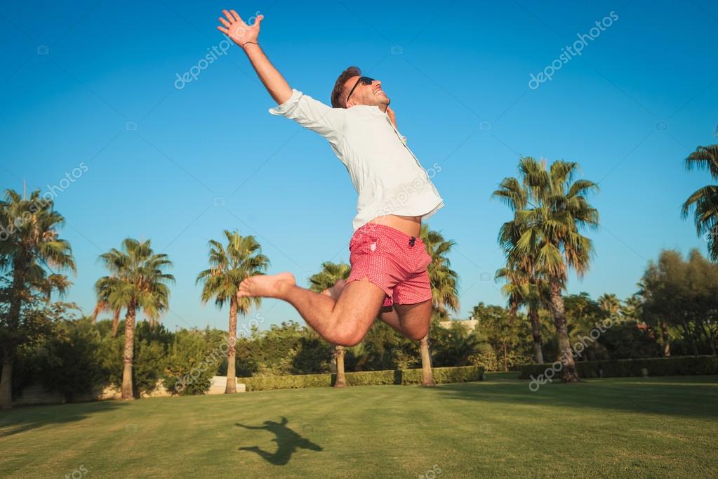 Ecstatic young casual man jumping of joy outside Stock Photo by ...