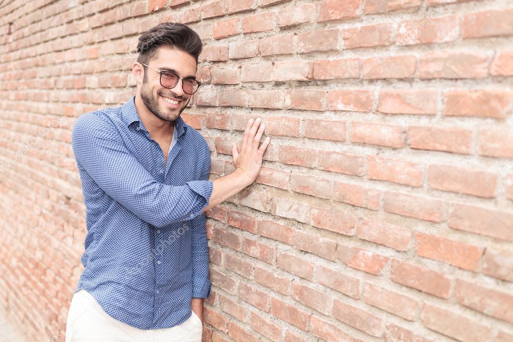 Smiling casual man touching brick wall Stock Photo by ©feedough 52425087 Smiling casual man touching brick wall Stock Photo by ©feedough 52425087