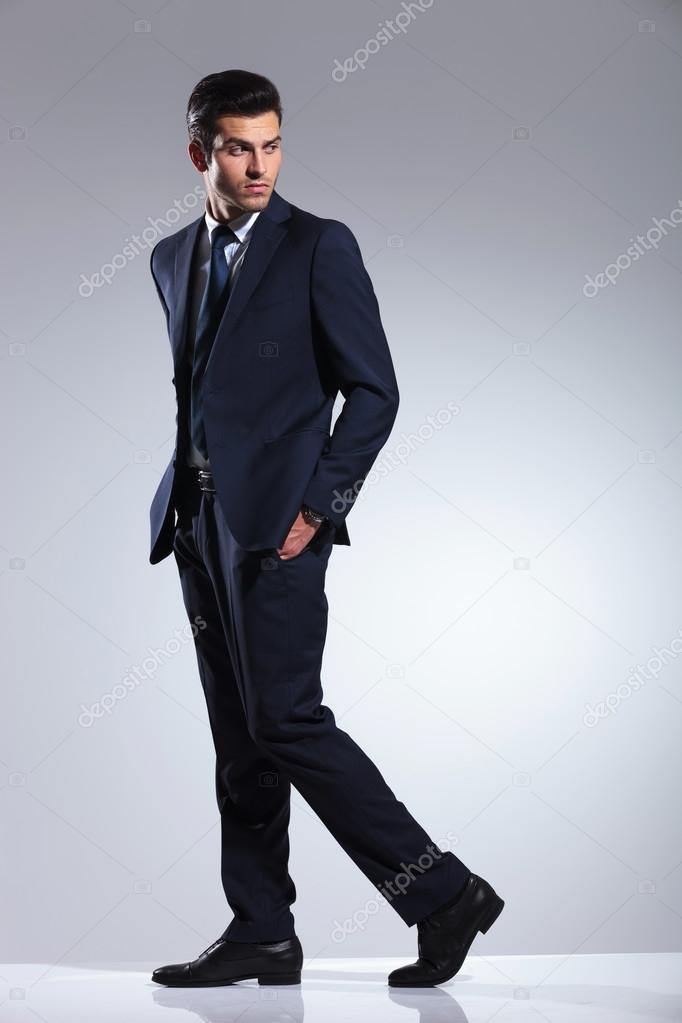 Young business man walking on grey studio background — Stock Photo ...