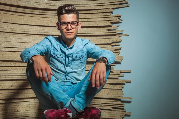 Smart man sitting in studio with hands on knees - Stock Image - Everypixel