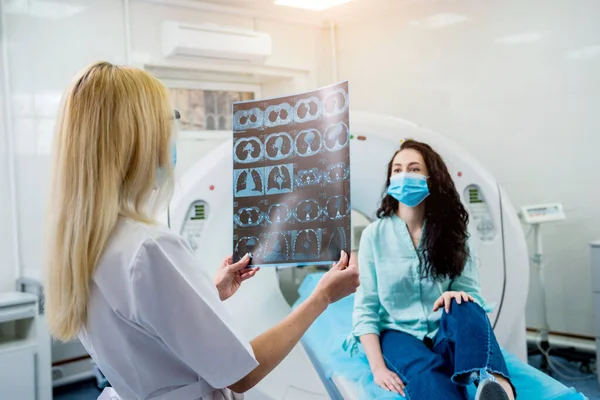Radiologist with a female patient wearing protective masks examining a ...