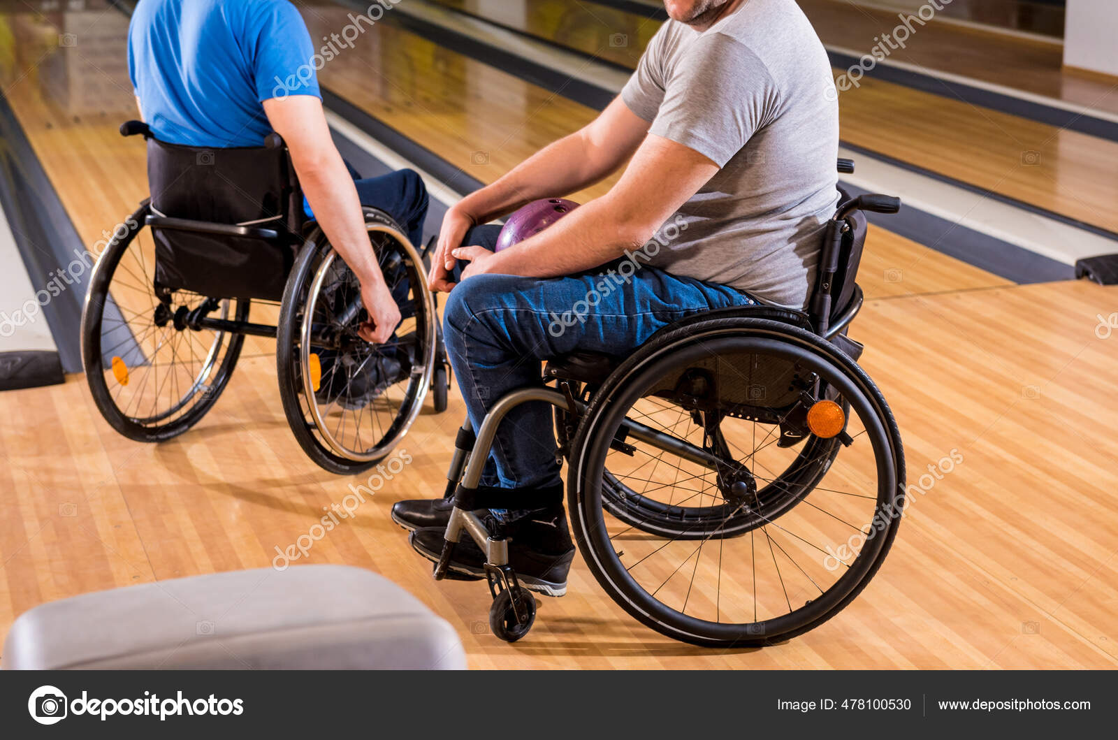 Two young disabled men in wheelchairs playing bowling in the club ...