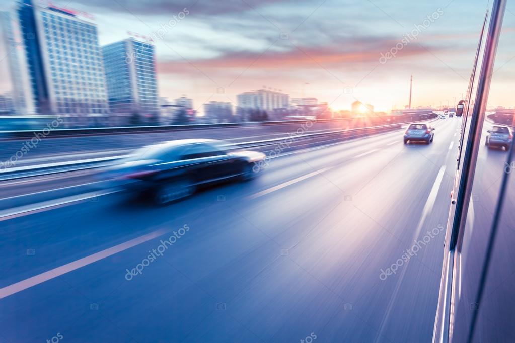 Coche conduciendo en la autopista al atardecer, desenfoque de ...
