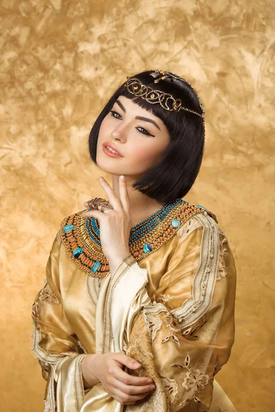 Beautiful woman like Egyptian Queen Cleopatra on golden background ...