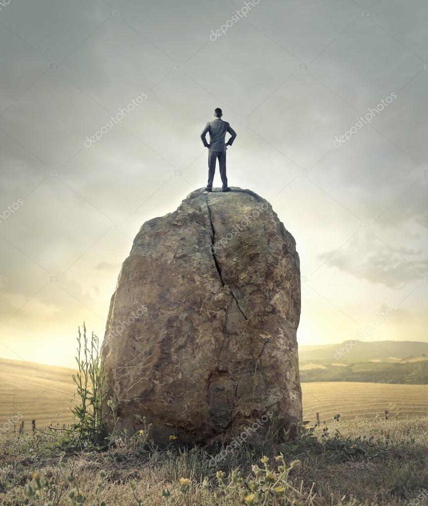 Businessman standing on a rock Stock Photo by ©olly18 79873654