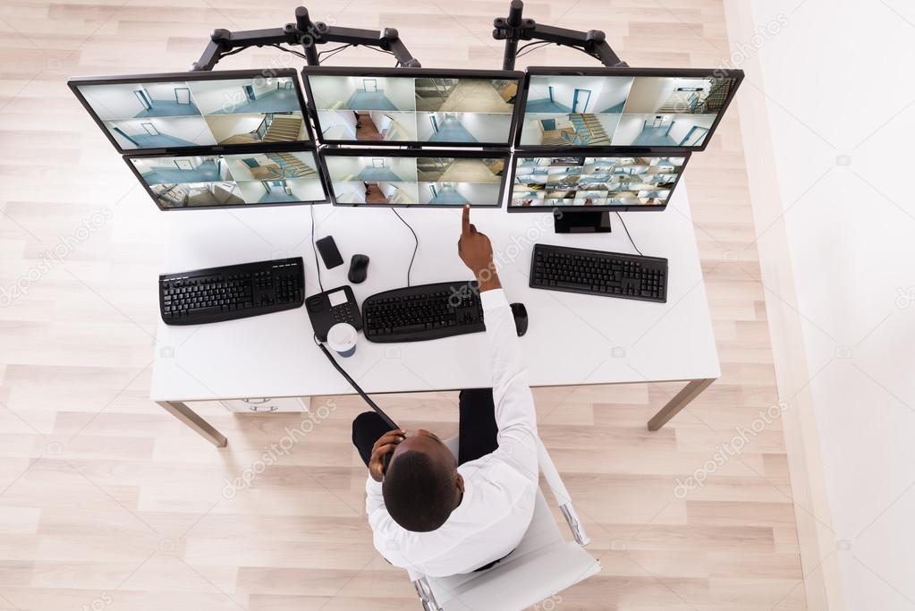 Operador masculino señalando imágenes de CCTV en la computadora 2022