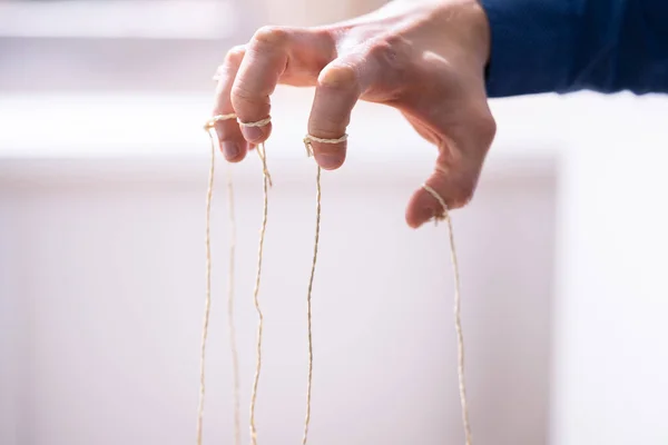 Hand Holding Puppet Strings