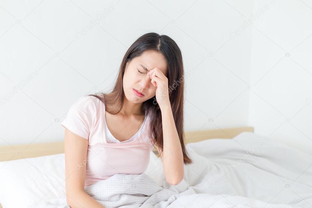Woman feeling headache and sitting on bed — Stock Photo © leungchopan ...