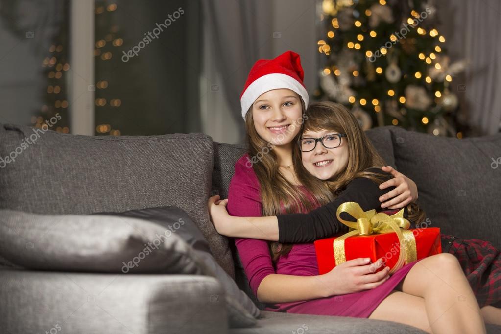 Girl hugging sister on sofa — Stock Photo © londondeposit #57272953