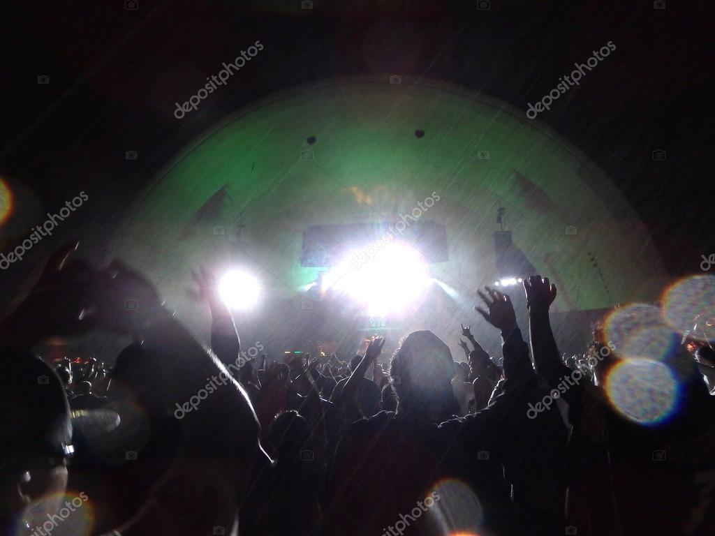 Shaggy sings on stage in the rain as crowd dances and waves hand ...