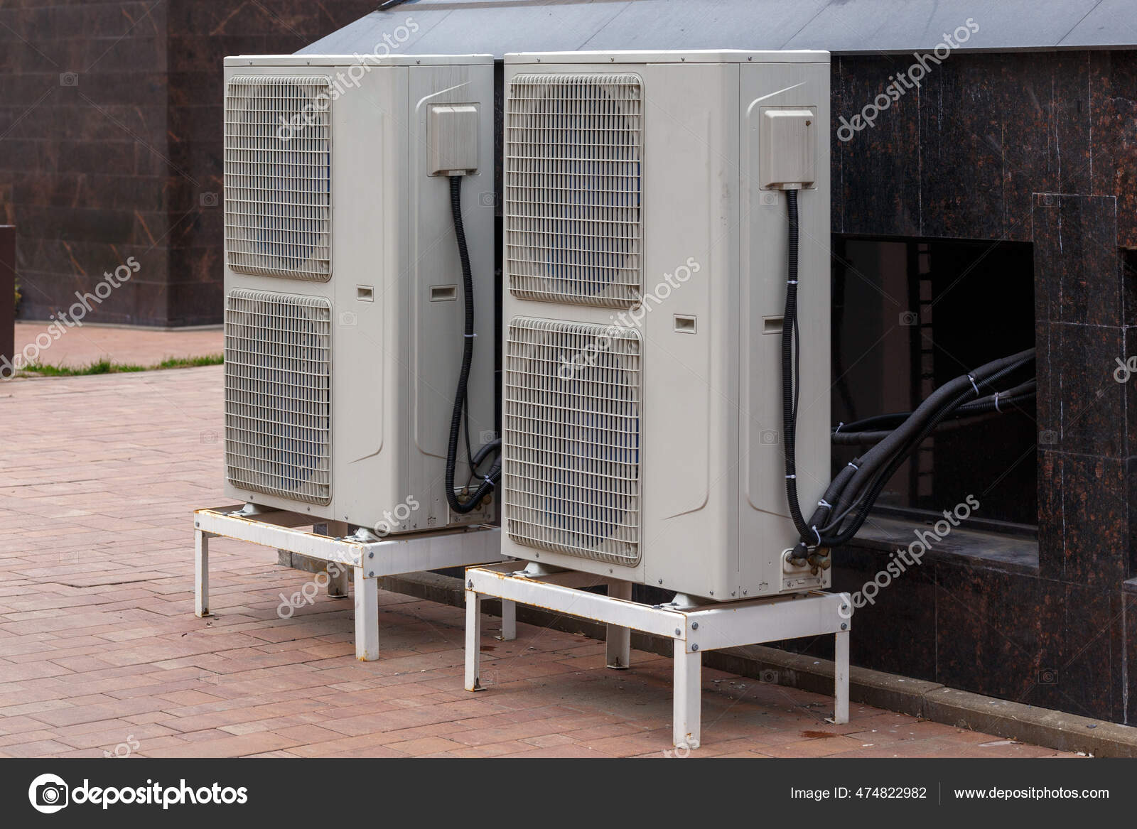 Two double condensing units of air conditioner on the ground level near ...