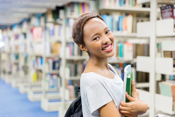 College student holding books in library - Stock Image - Everypixel