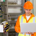 Engineer with laptop in machine control room Stock Photo by ...