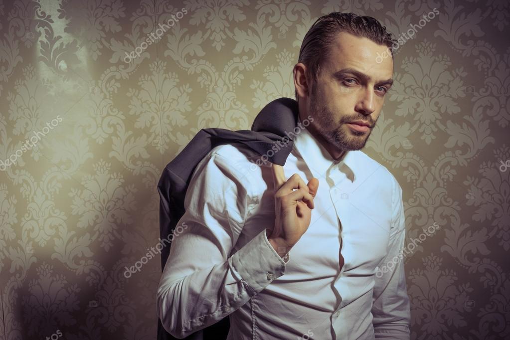 Young handsome man holding a jacket posing isolated over vintage ...