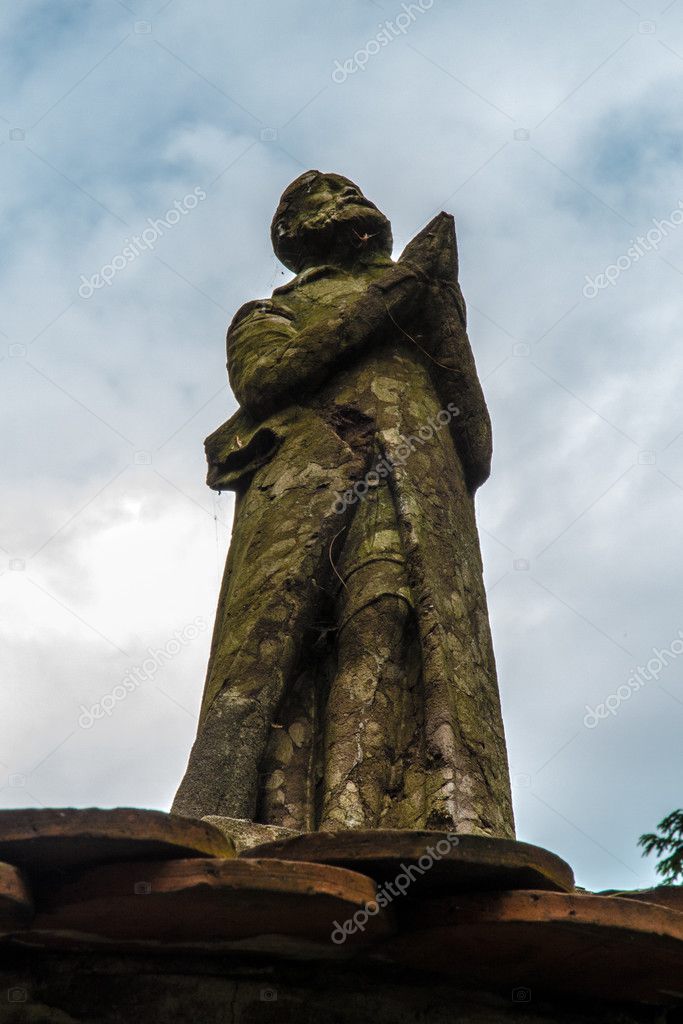 Figura de monje orante en la puerta que conduce al cementerio, el 2022