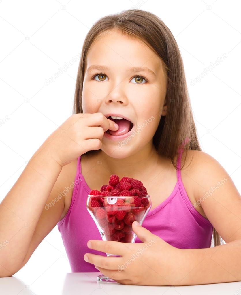 Happy little girl is eating raspberries Stock Photo by ©Kobyakov 54367597