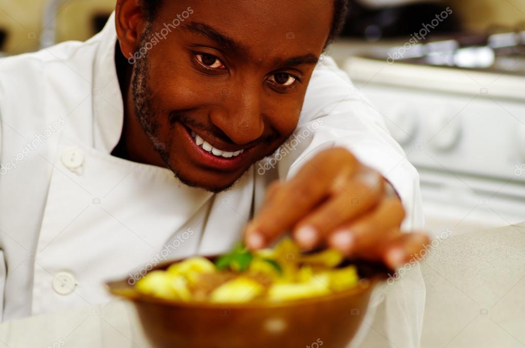Happy chef wearing white clothes preparing bowl of food in professional ...
