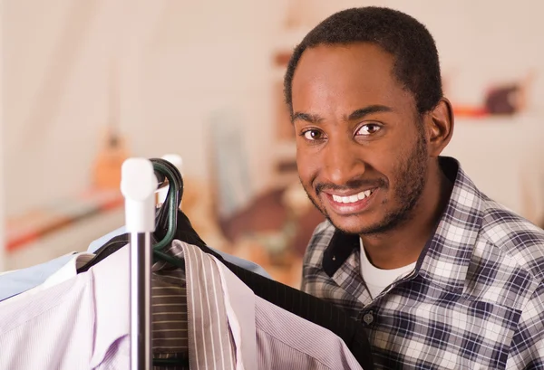 Handsome young man standing inside wardrobe going through rack of ...