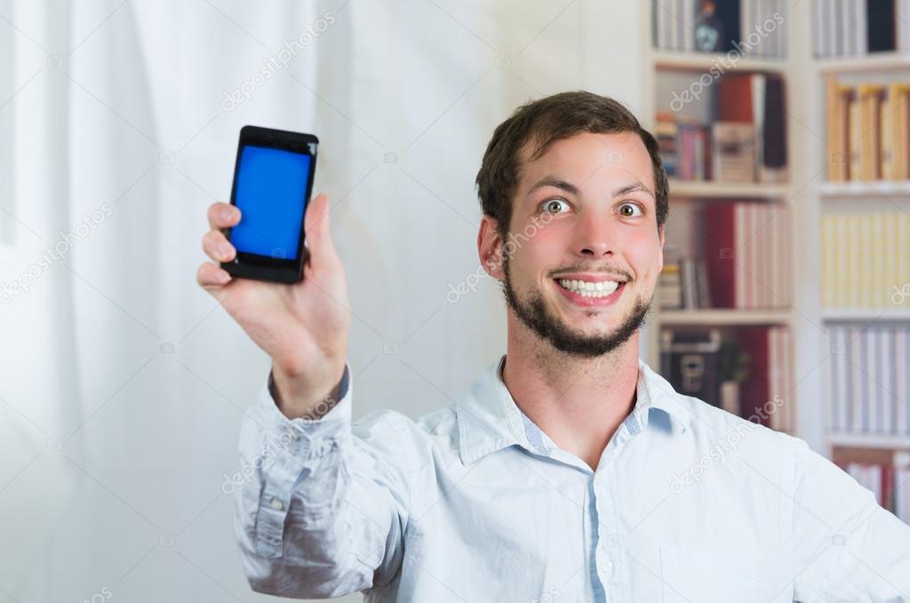 Young happy man holding his cell phone and showing the screen — Stock ... Young happy man holding his cell phone and showing the screen — Stock ...