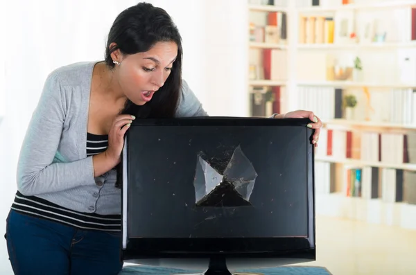 Brunette female looking over broken computer screen with shocked facial ...