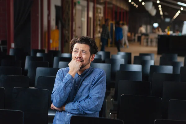 Scared man sitting in conference hall - Stock Image - Everypixel