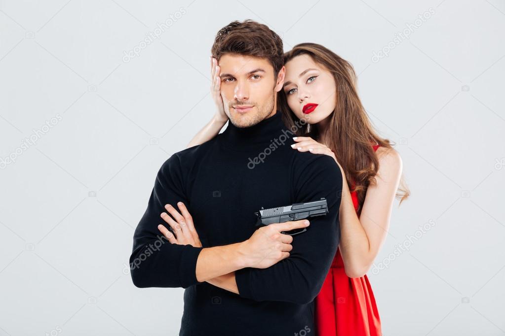 Beautiful young couple hugging and posing with gun Stock Photo by ...