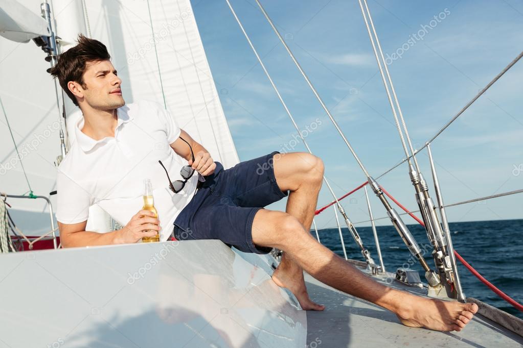 Handsome young man drinking beer while resting on the yacht Stock Photo ... Handsome young man drinking beer while resting on the yacht Stock Photo ...