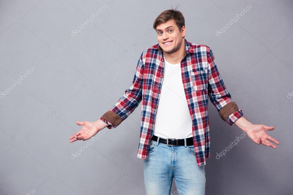 Confused cute young man standing and shrugging Stock Photo by ...