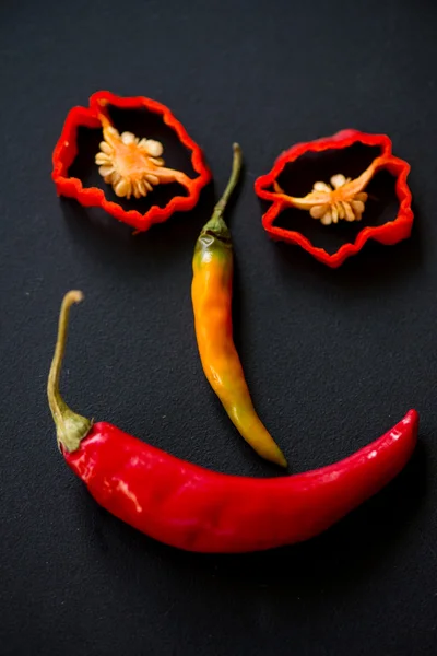 Smiling funny face made with hot chilli peppers on black slate - Stock ...