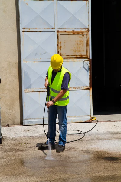 Road worker spraying bitumen emulsion with the hand spray lance before ...