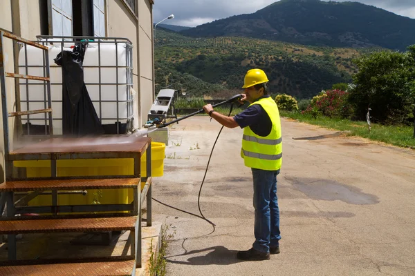 Worker in hard hat pressure washing - Stock Image - Everypixel