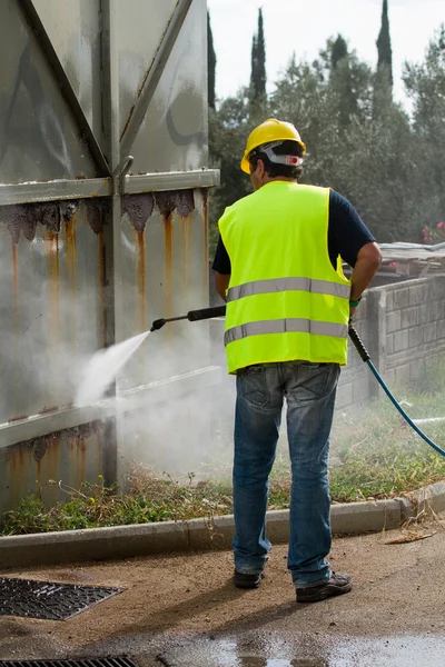 Worker in hard hat pressure washing - Stock Image - Everypixel