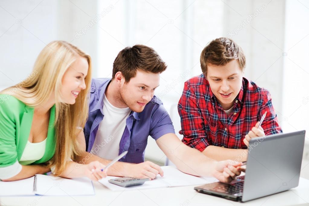 Smiling students looking at laptop at school — Stock Photo © Syda ...