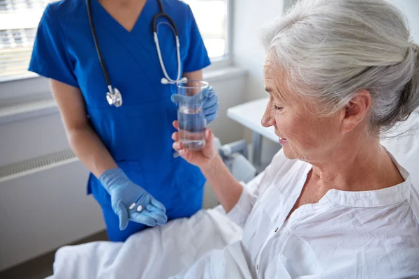 Doctor giving medicine to senior woman at hospital Stock Photo by ©Syda ...