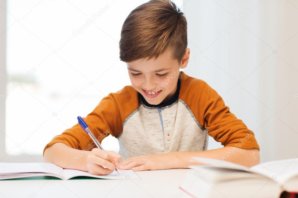Smiling student boy writing to notebook at home — Stock Photo © Syda ...