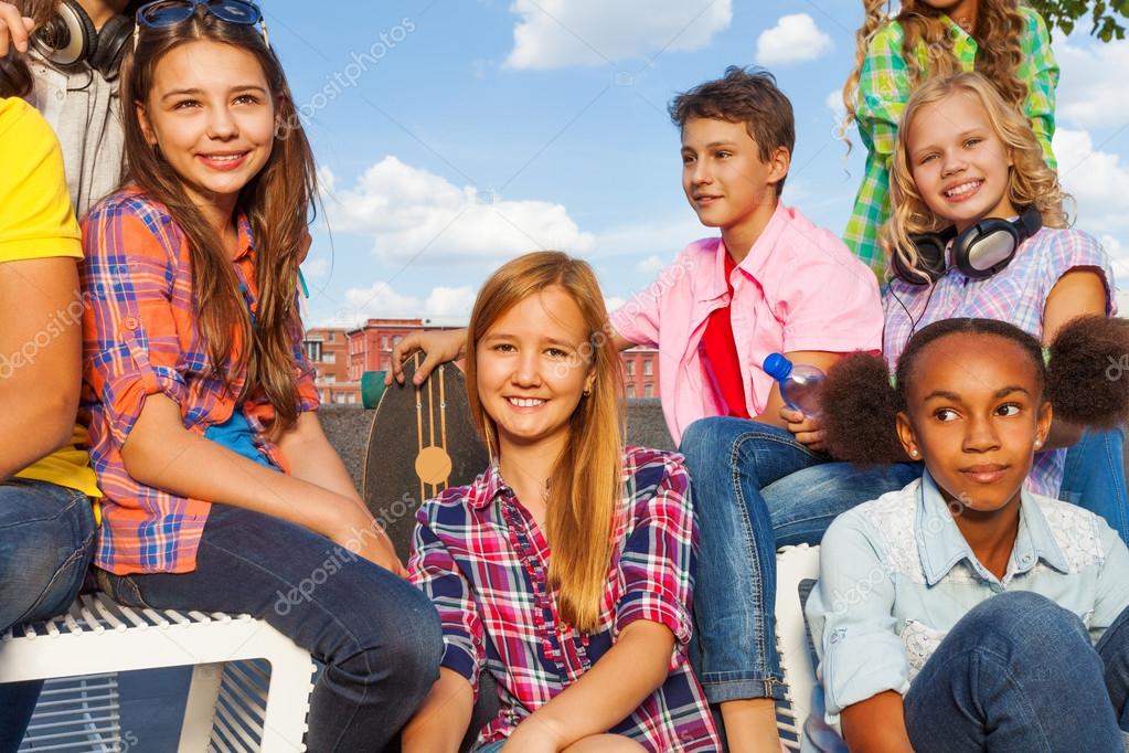 Friends sitting on chairs of embankment Stock Photo by ©serrnovik 60876519