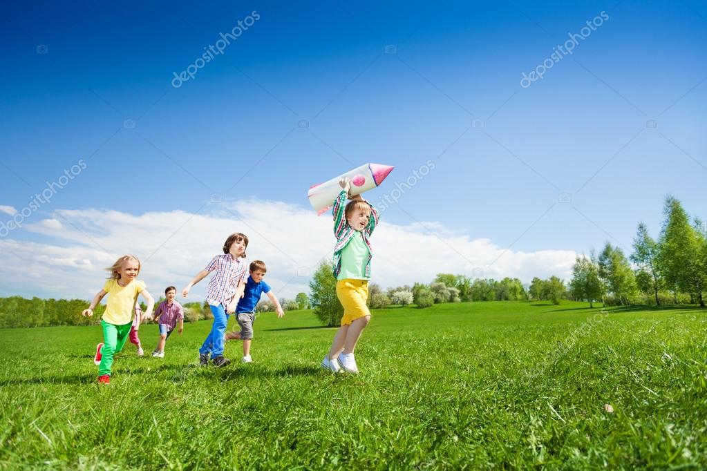 Children run after boy holding rocket — Stock Photo © serrnovik #77387906