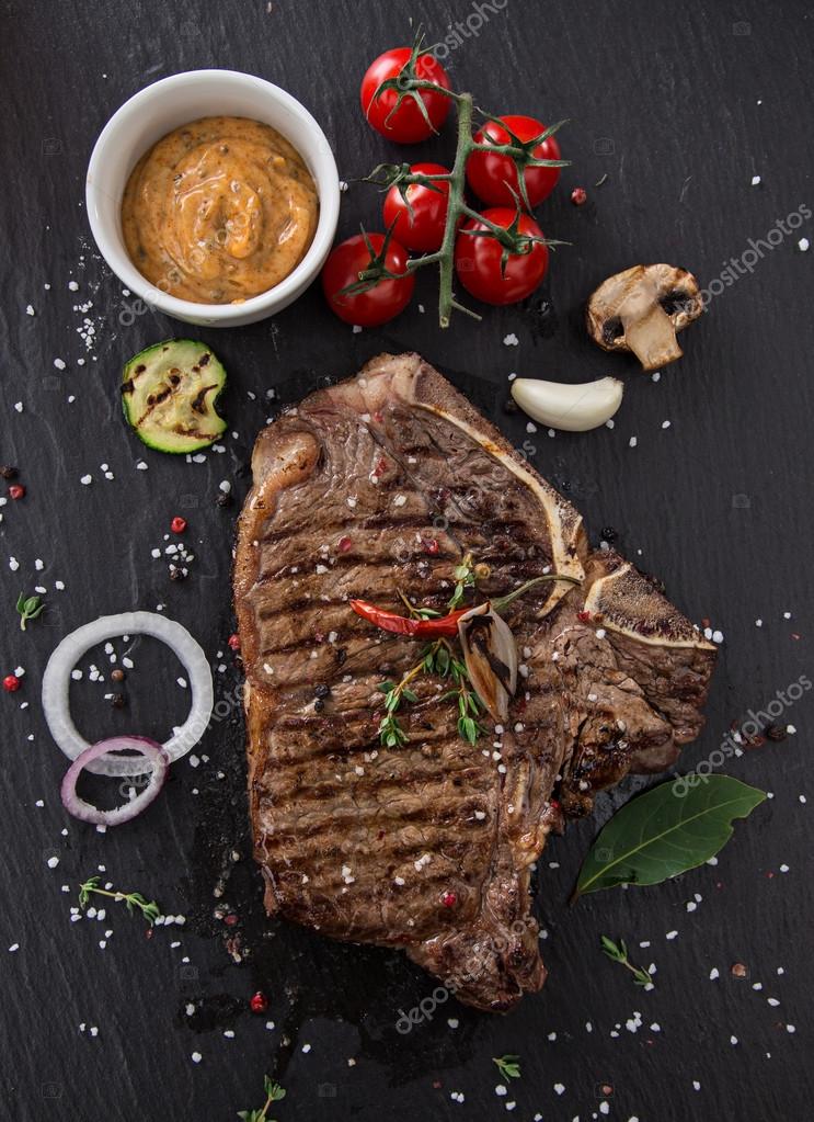 Beef t-bone steak on black stone table Stock Photo by ©Kesu01 70178315
